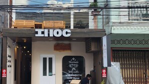 A building with a sign reading "THIOC" and a massage clinic sign below. There are steps leading to the entrance, a motorcycle parked outside, and a clear sky.