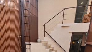 Uma piscina com borda azulejada, uma escada com corrimão e um muro com uma placa.