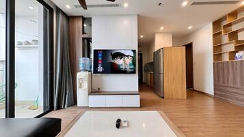 Uma sala de estar moderna com televisão, dispenser de água e ventilador de teto.
