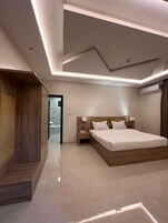 Um quarto moderno com uma cama grande, cabeceira de madeira e mesas de cabeceira embutidas.