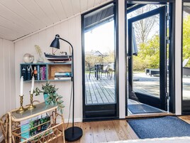 Quarto com estante, escrivaninha, luminária e uma grande porta de vidro deslizante que dá para um deck externo.