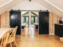 Um loft espaçoso com pé-direito alto, piso de madeira, área de refeições com cadeiras, uma cama e cozinha.