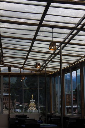 Um restaurante com teto de vidro, mesas e cadeiras.