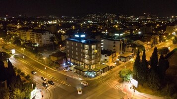 Hotel de vários andares com fachada de vidro moderna, situado numa interseção urbana.