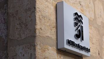 Placa do MB Boutique Hotel fixada em parede texturizada.