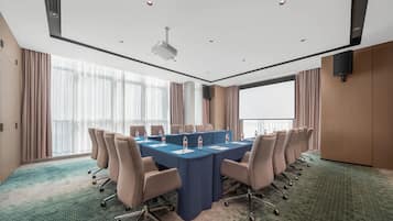 Uma sala de conferências com uma mesa comprida, cadeiras, um projetor e uma tela grande.