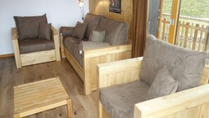 Sala com piso de madeira, três sofás e uma pequena mesa de madeira.