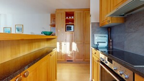 Uma cozinha moderna com armários de madeira, bancada de granito, micro-ondas embutido e fogão de aço inoxidável.