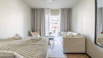 Quarto de hotel com cama, sofá, uma mesinha e espelho.