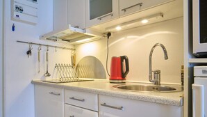 Uma cozinha moderna com uma pia de aço inoxidável, uma chaleira vermelha e um suporte para chaleira.