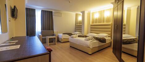 Quarto de hotel com uma escrivaninha de madeira, duas camas, uma cadeira e um guarda-roupa grande.
