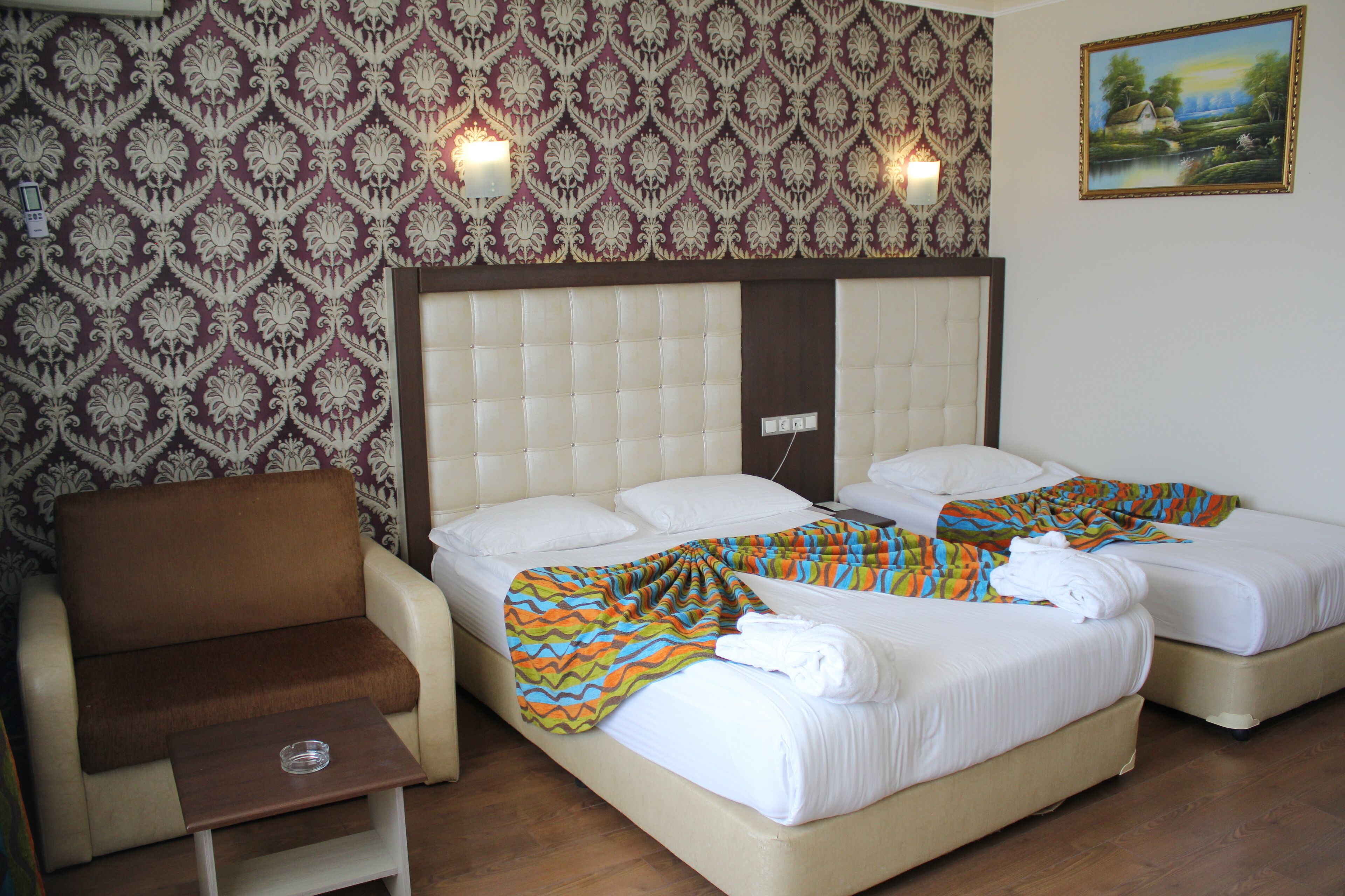 Quarto de hotel com duas camas, um sofá e uma mesinha.