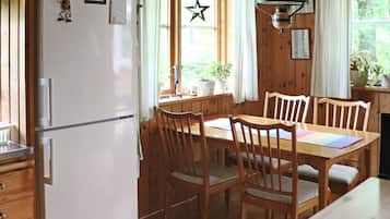 Uma mesa de jantar de madeira com cadeiras, um refrigerador branco e um lustre.