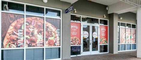 Restaurante de pizza com grandes janelas exibindo anúncios de pizza.
