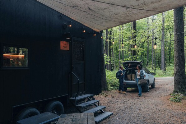 Uma motorhome preta com deck de madeira e degraus que levam a uma área coberta.