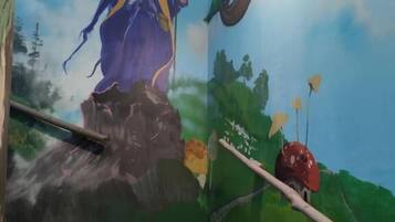 Um mural retrata um mago numa ramagem, com uma varinha, um cogumelo vermelho e um céu azul.