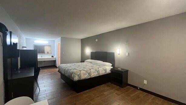 Quarto com cama, mesas de cabeceira, escrivaninha e espelho.