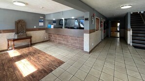 Um hall amplo com balcão de recepção, um banco de madeira e um extintor de incêndio.