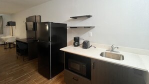 Cozinha compacta com geladeira, micro-ondas e pia.