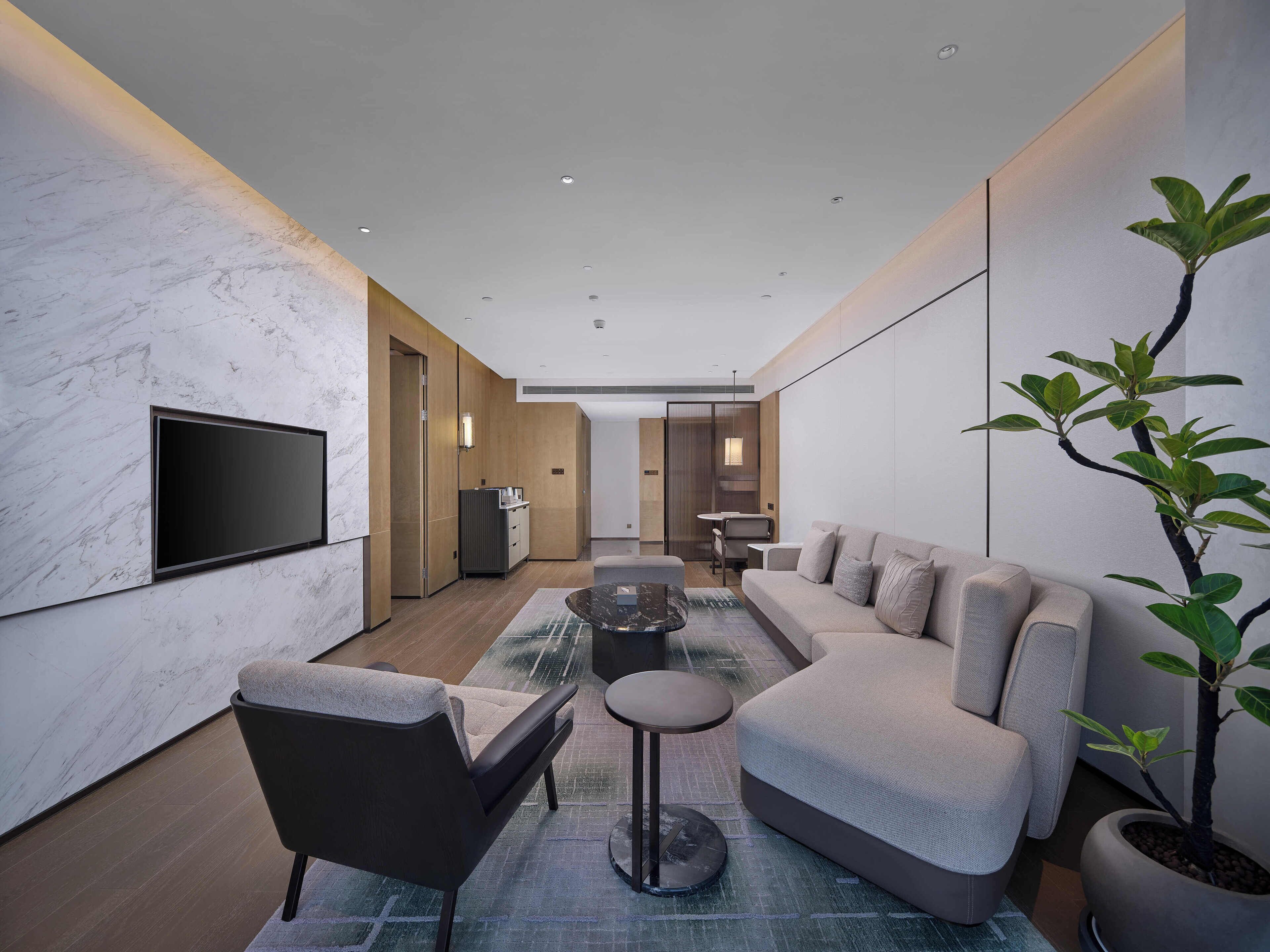 Uma sala de estar moderna com um sofá modular, uma mesa de centro e uma TV fixada na parede.