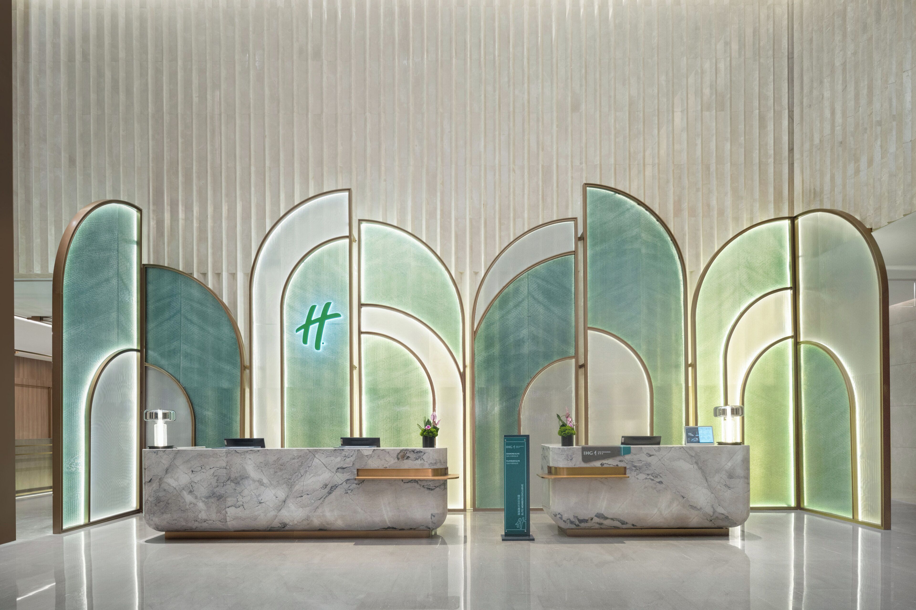 Uma área de recepção com balcões de mármore, um letreiro de neon e design moderno.