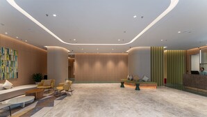 Um hall amplo com piso de mármore, áreas de estar e uma mesa de recepção.