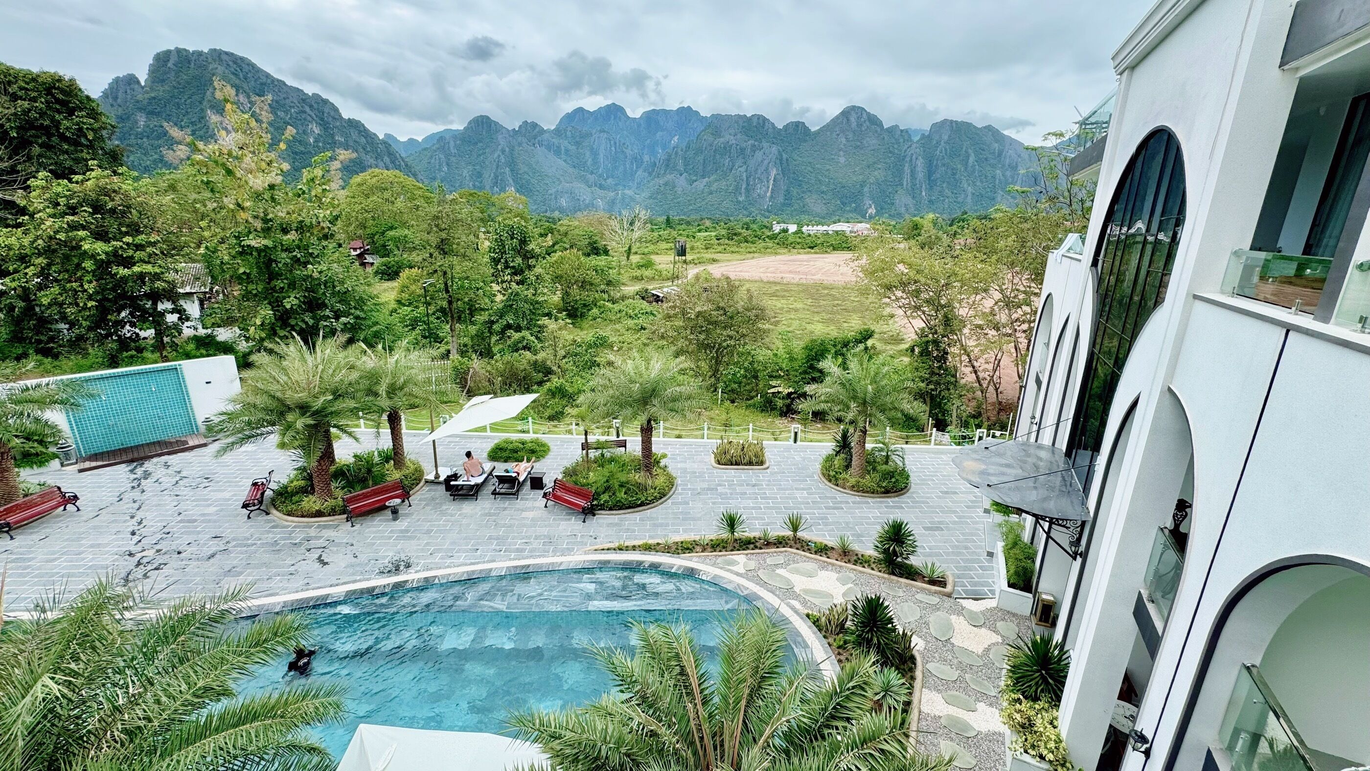 Área de piscina com espreguiçadeiras e vista para montanhas.