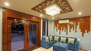 Uma sala de estar moderna com um sofá seccional, uma mesa de centro de vidro e um lustre decorativo.