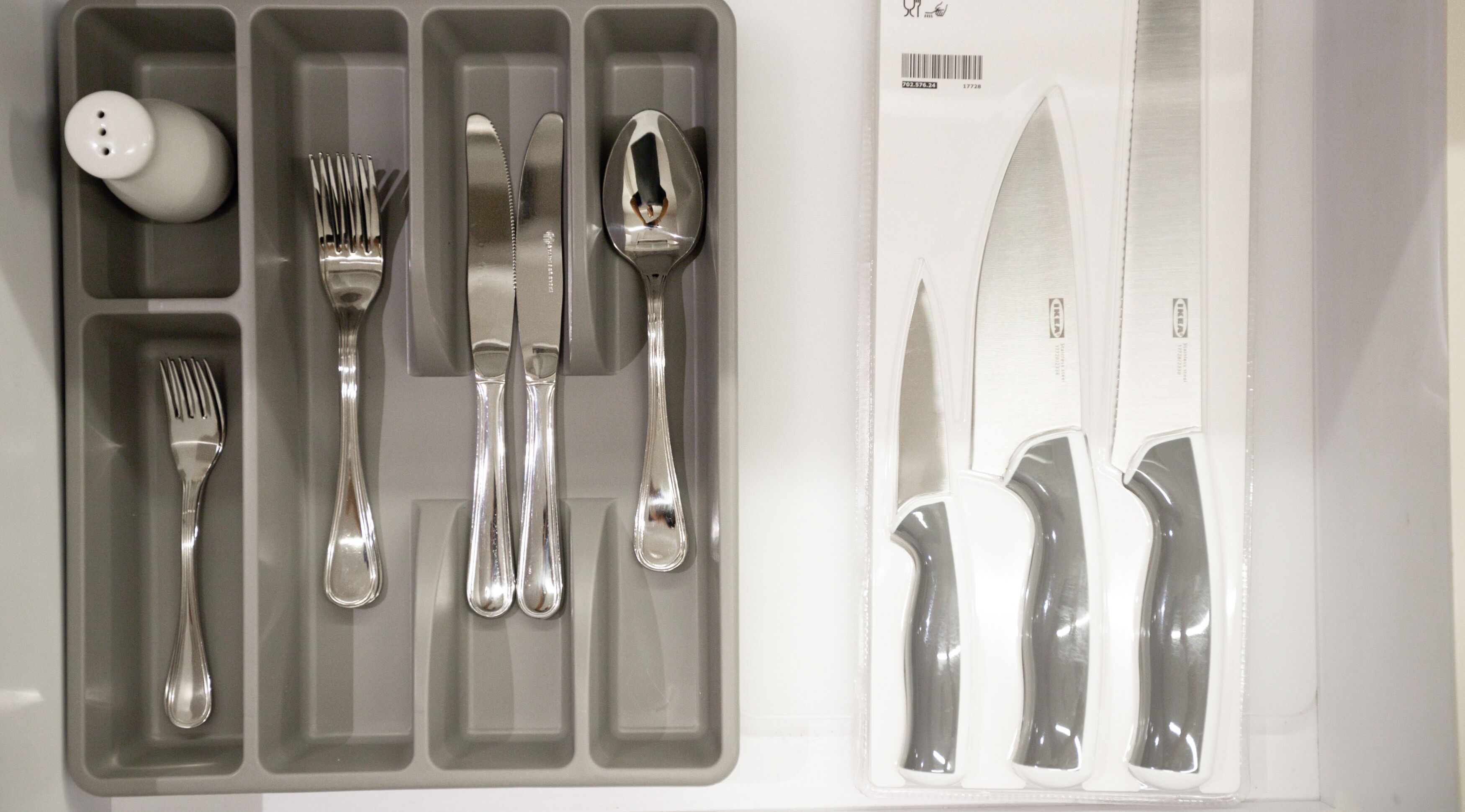 Um conjunto de talheres organizados em uma bandeja com divisórias, incluindo garfos, facas e colheres.