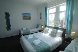Quarto de hotel com duas camas, um quadro, uma janela com cortinas e uma mesa de cabeceira com abajur.