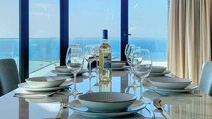 Mesa de jantar posta para seis pessoas, com uma garrafa de licor, copos e pratos, com vista panorâmica.