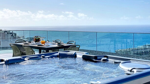Uma área de piscina no terraço com mesa e cadeiras, com vista para uma grande extensão de água.