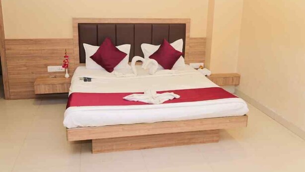A neatly made bed with a wooden headboard, white and red bedding, and a decorative swan pillow arrangement.