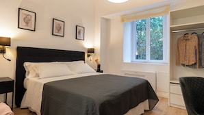 Quarto com cama, mesas de cabeceira, janela com vista e guarda-roupa.