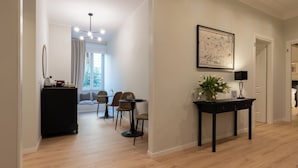 Uma sala de estar moderna com área de jantar, uma mesa consola preta com um vaso e um mapa emoldurado na parede.