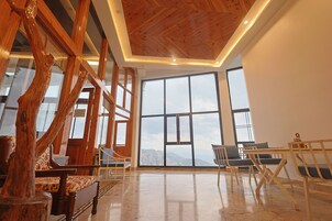 Quarto espaçoso com grandes janelas, mobiliário de madeira e piso lustrado.