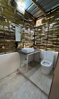 Casa de banho pequena com lavatório branco, sanita e espelho pequeno.