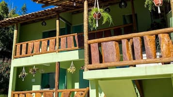 Um edifício de dois andares com fachada verde e varandas de madeira.