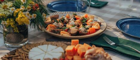 Uma mesa posta com diversos alimentos, incluindo um prato de legumes, uma tigela de frutas e um copo de água.