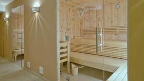 Uma sala de sauna com banco de madeira, portas de vidro e espelho na parede.
