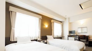 Quarto de hotel com duas camas, uma escrivaninha com computador, uma cadeira e uma televisão.