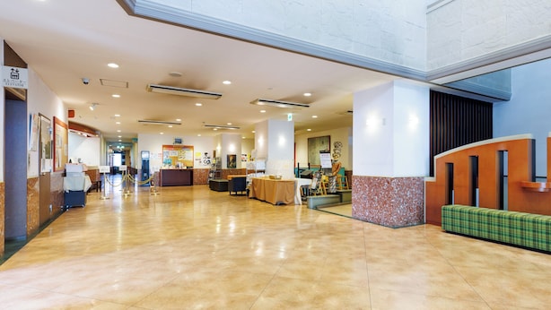Um hall amplo com balcão de recepção, área de estar e vista desobstruída para o elevador.