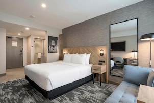 Quarto de hotel com uma cama grande, mesas de cabeceira, uma escrivaninha, uma cadeira e um espelho.