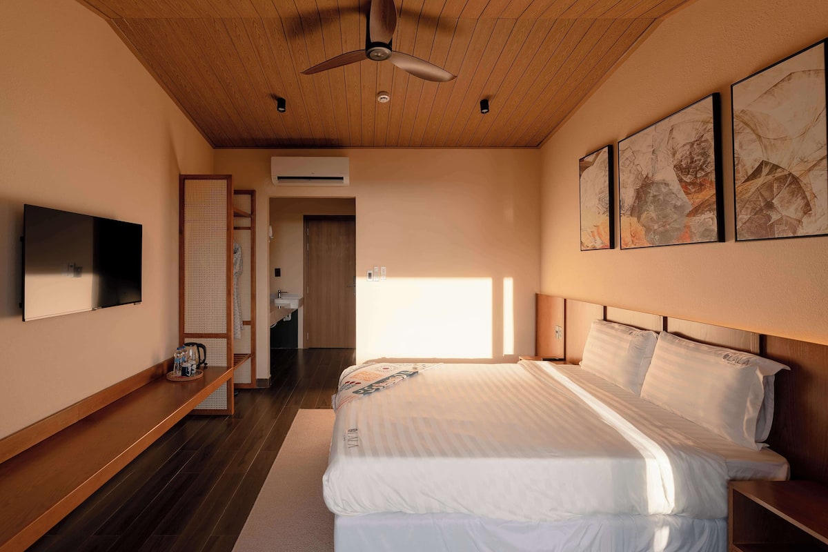 Quarto com cama, televisão, teto de madeira e obras de arte na parede.