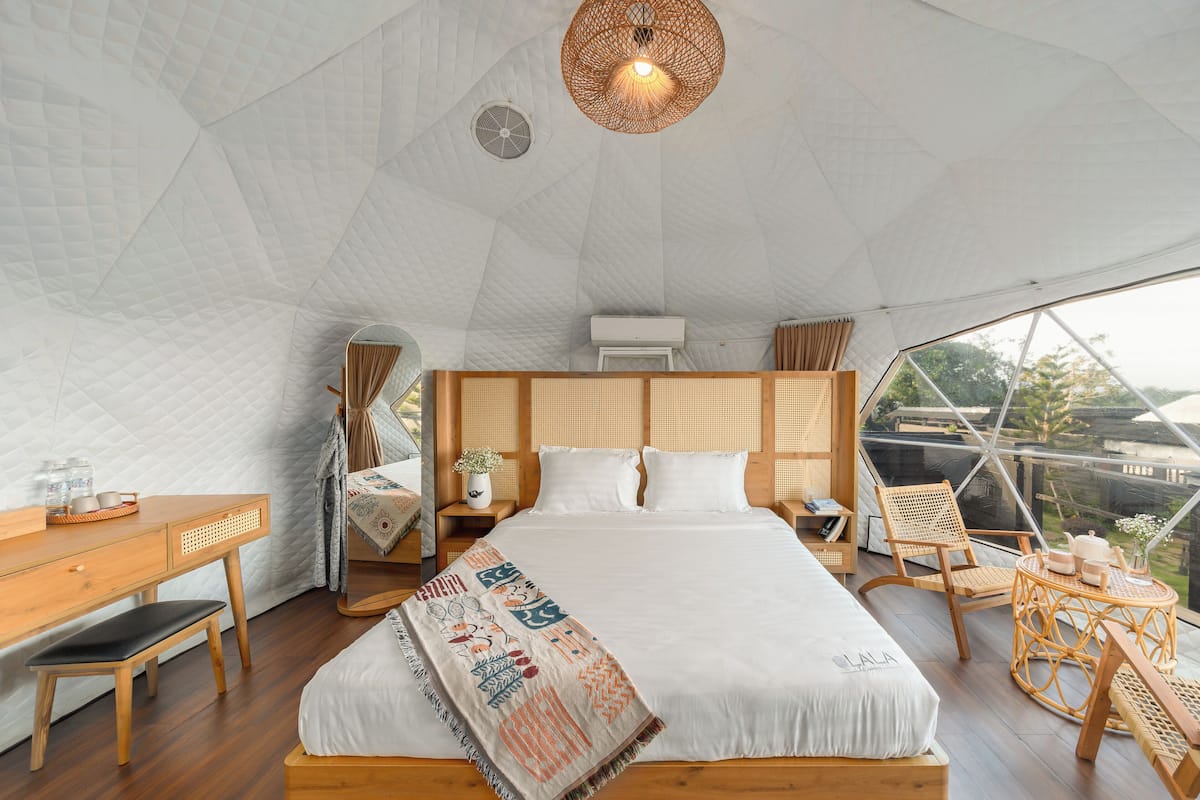 Um quarto em estilo tenda, amplo e bem iluminado, com uma cama grande, móveis de madeira e vista para o exterior.
