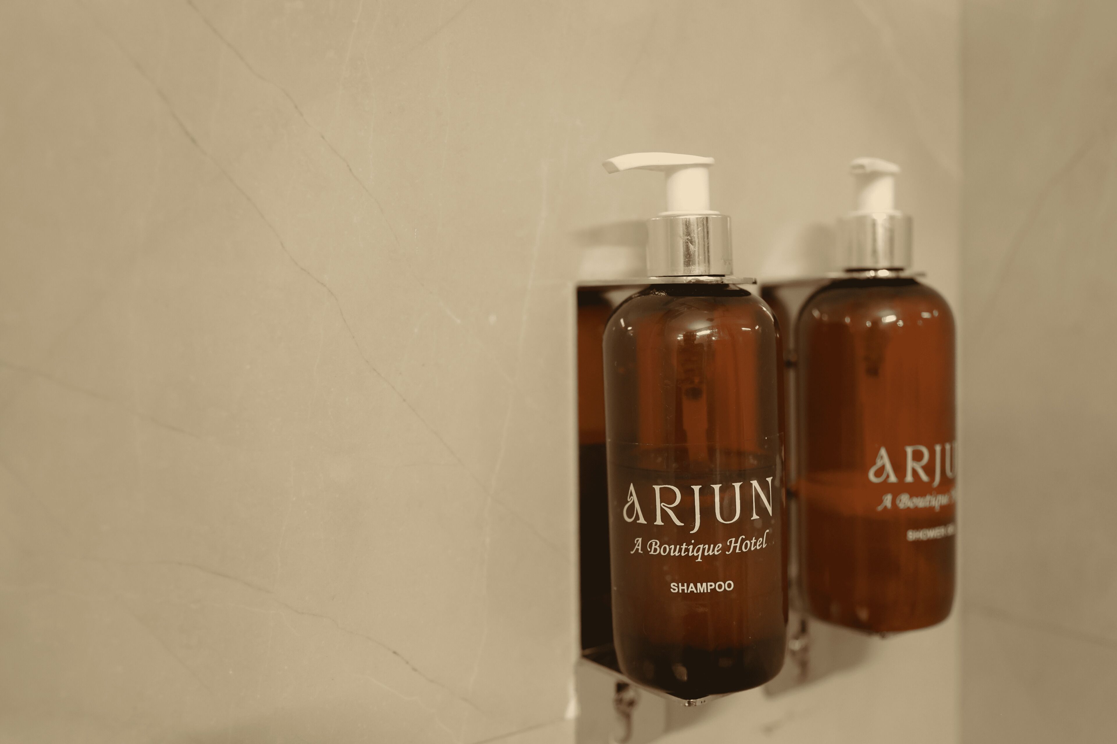 Dois frascos de shampoo do Arjun A Boutique Hotel em um banheiro.