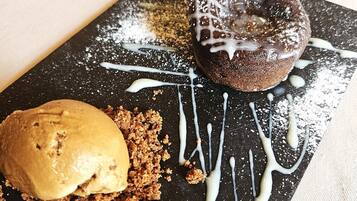 Um prato de sobremesa com bolo de chocolate, uma bola de sorvete e biscoitos esfarelados.