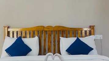 Uma cama com cabeceira de madeira, dois travesseiros azuis e um cobertor branco.