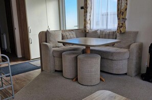 Uma sala de estar aconchegante com uma mesa de madeira redonda, um sofá e pufes.