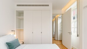 Quarto com cama, guarda-roupa, mesa de cabeceira e janela.